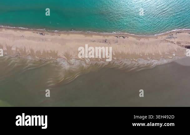 Aerial view of long thin sand tombolo separating turquoise sea and calm ...