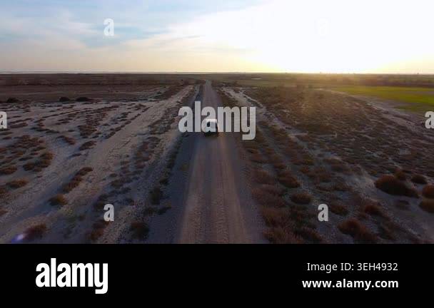 Car driving toward sunset on endless desert road symbolizing journey ...