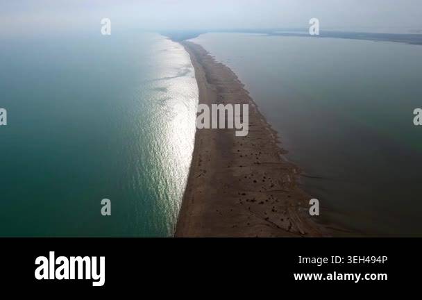 Aerial view of long thin sand tombolo separating turquoise sea and calm ...