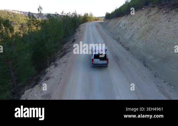 Aerial view of vehicle driving along winding mountain road through ...