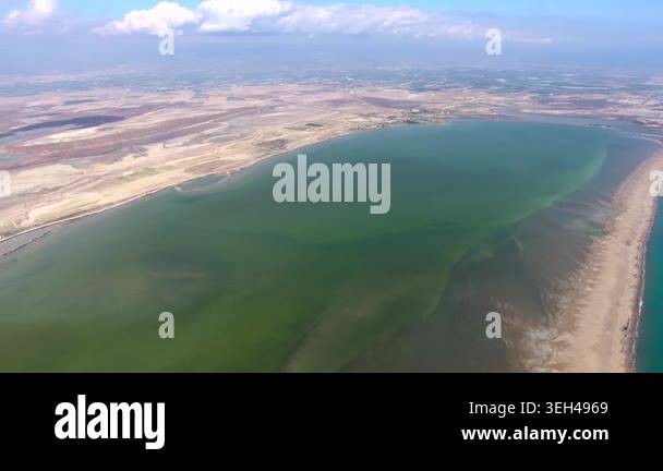 Aerial view of long thin sand tombolo separating turquoise sea and calm ...