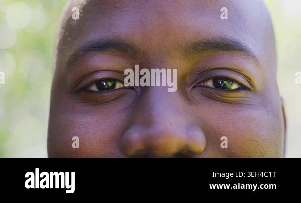 Adult African man engaging camera, smiling as camera pulling back ...