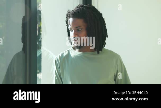 African American man by glass door in lightgreen long-sleeve shirt ...