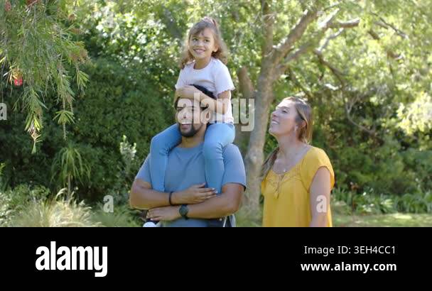 Family spotting red pods on tree in garden, parents supporting child on ...