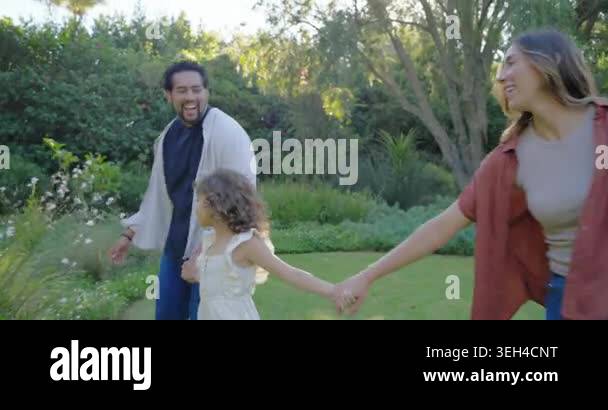 Diverse family walking in yard, child spotting flowers and skipping ...