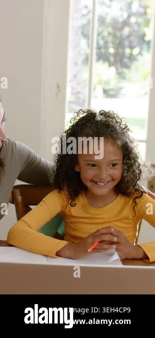 Vertical video: Diverse mother guiding daughter drawing on laptop using ...