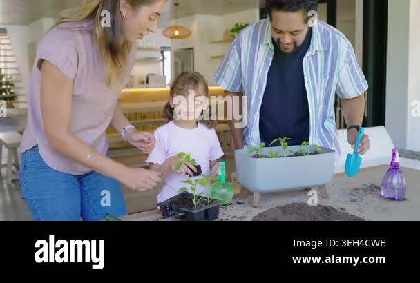 Family of three planting seedlings at kitchen patio planter, child ...