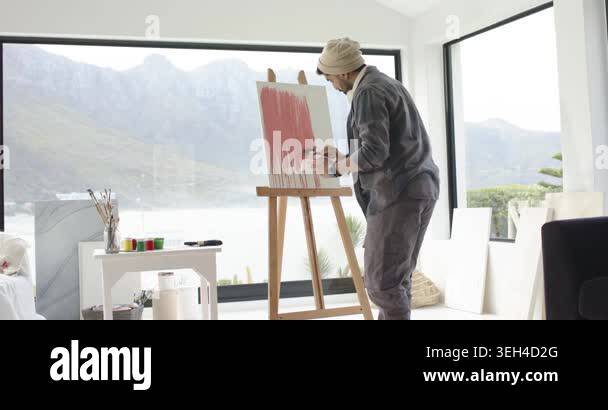 With canvas blank, artist is dipping brush in red paint then brushing ...