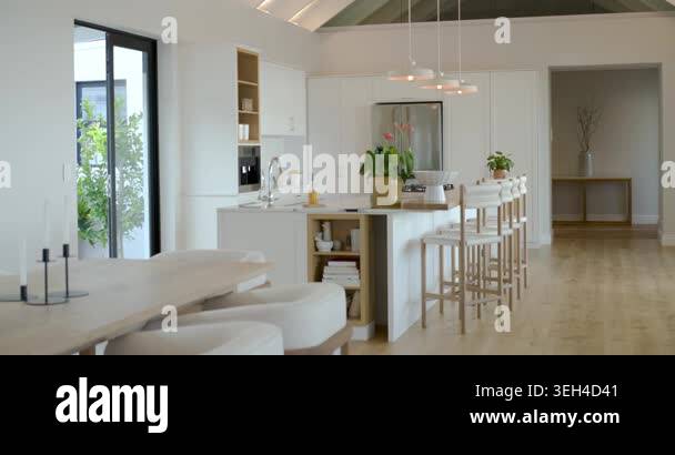 Camera is panning right revealing island, stools and dining table by ...