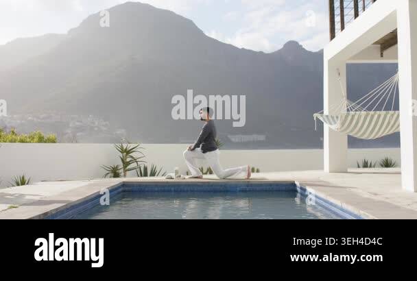 Indian male starting stretch by stepping into high lunge on yoga mat ...