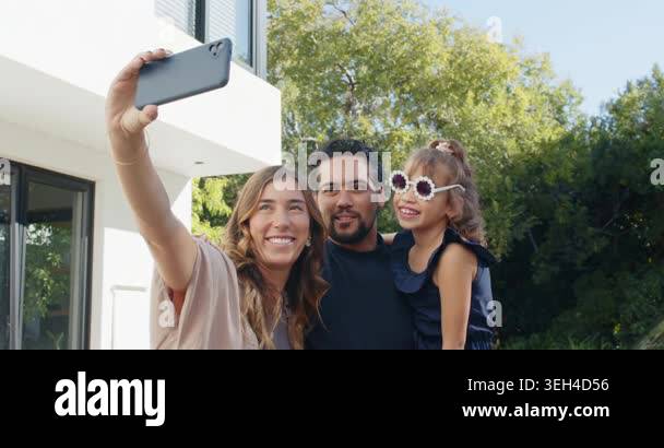 Diverse family with woman raising smartphone, taking selfie, then ...