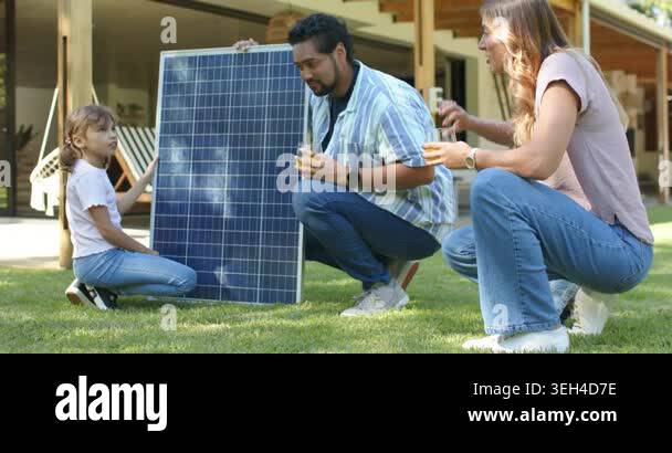 African American family crouching in yard by solar panel, child ...