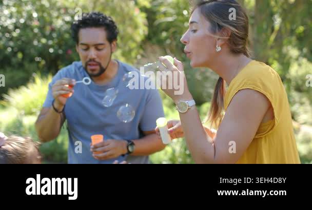 Diverse couple dipping wands into orange-top and white bottles blowing ...