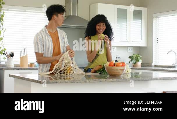 Couple unpacking reusable bags in kitchen after grocery shopping ...