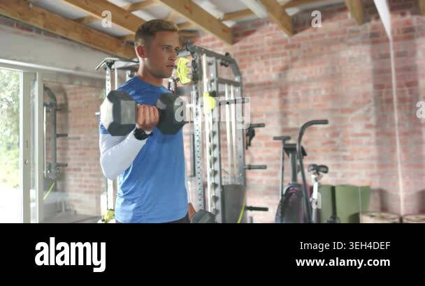Man curling hex dumbbell in home gym to build strength, camera shifting ...
