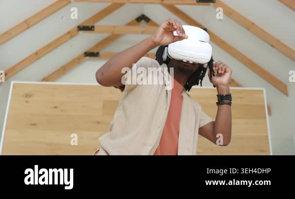 African American man in loft adjusting white VR headset, reaching and ...