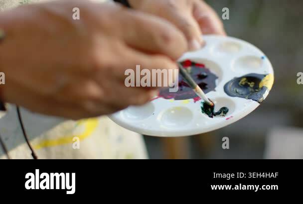 Senior Asian man wearing apron holding studio palette, dipping brush ...