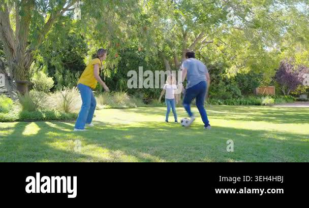 Family with child kicking soccer ball, parents passing and coaching ...