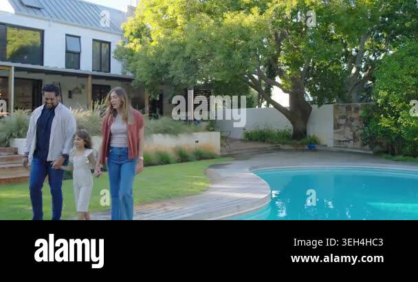 Diverse family walking stepping off pool border onto grassy lawn ...