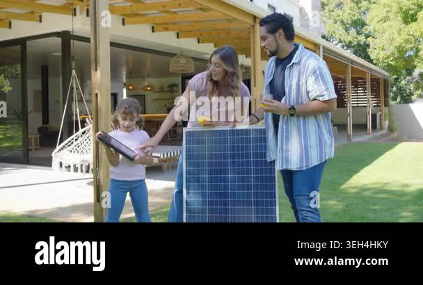 Family parents guiding, pointing, daughter raising small panel in yard ...