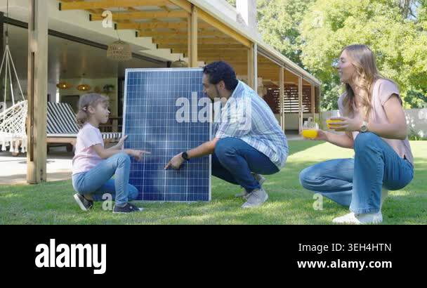 Diverse family placing solar panel on backyard lawn at covered patio ...