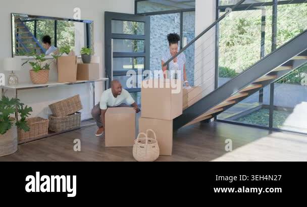 Diverse couple carrying moving boxes after van arrival stacking in ...