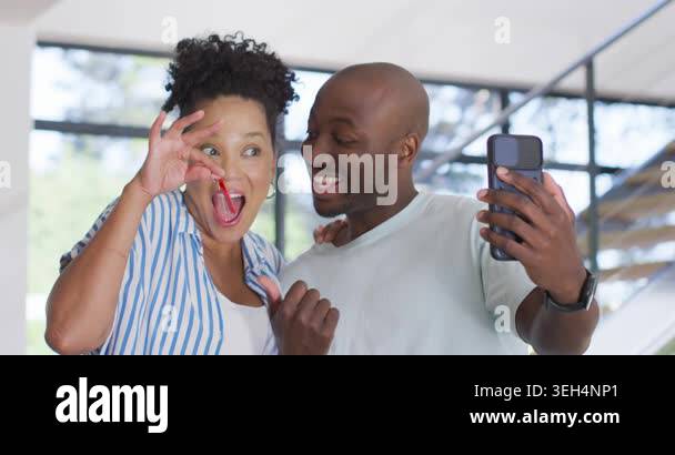 African American couple receiving live call, holding smartphone ...