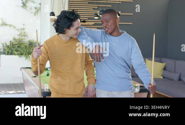 Draping arm around companion's shoulders, diverse male friends chatting ...