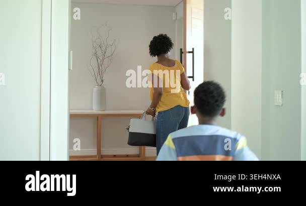 African American mother and son entering home, front door opening ...