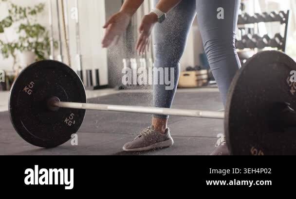 Hands clapping chalk over barbell on gym floor, chalk dust drifting ...