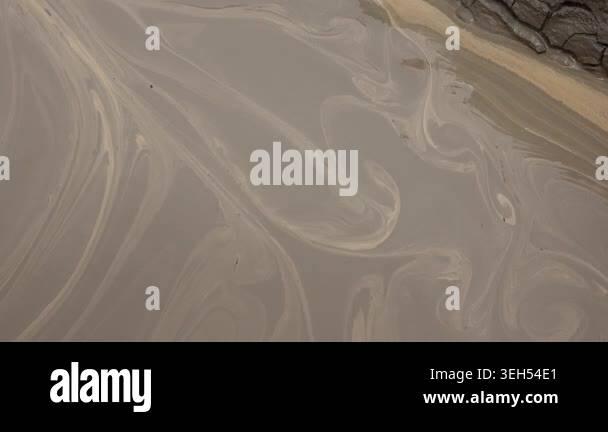 Muddy water swirls with thick sediment in a close industrial view of ...