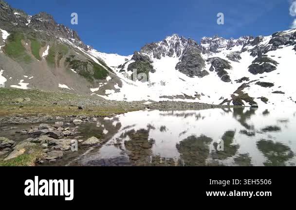 Cinematic Pyrenees border alpine lake below snowy peaks creates a ...