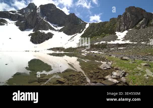 Cinematic Pyrenees border alpine lake below snowy peaks creates a ...