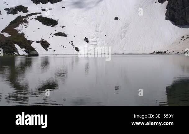 Cinematic Pyrenees border alpine lake below snowy peaks creates a ...