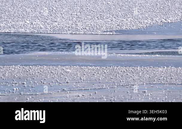 Frozen water surface holds ice sheets and cracks, winter stream or lake ...