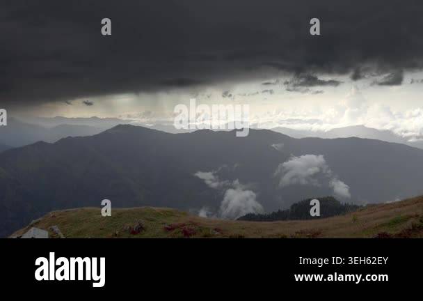 Storm clouds retreat above mountain plateau, wet grass slope, layered ...