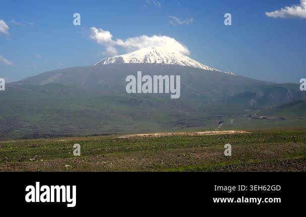 Mount Ararat snowy summit rises above green plain as clouds drift in ...