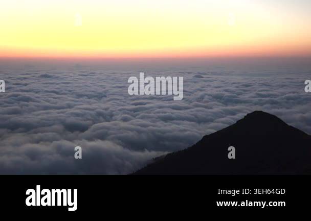 Sea of clouds from mountain peak at dawn, pastel sky over vast rolling ...