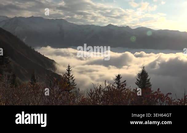 Alps mountain peaks rise above cloud sea as sunrays pierce mist ...