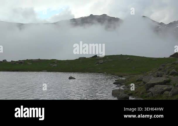 Fog drifts above alpine lake in Tibet Qinghai, treeless high altitude ...