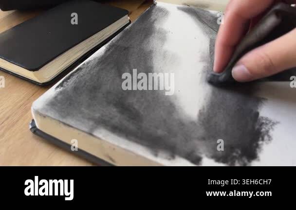Slow cinematic close up of a hand blending artistic charcoal on ...