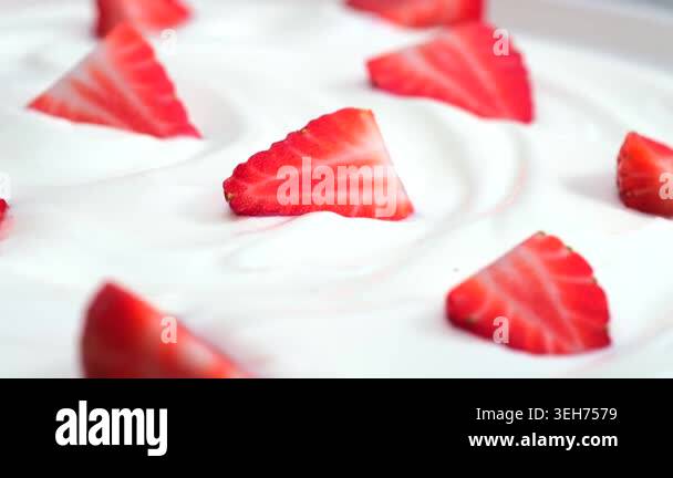 Juicy red strawberry pieces arranged on smooth white yogurt creating ...