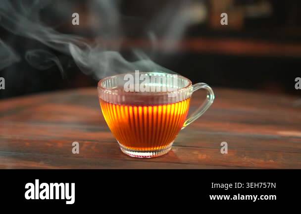 Hot amber tea in transparent glass cup with steam, slow motion, cozy ...