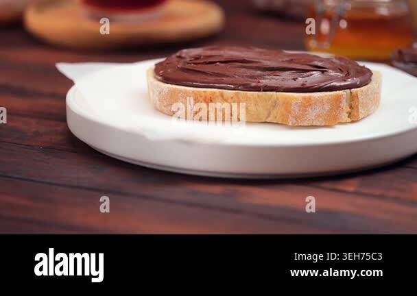 Creamy chocolate spreading with knife on soft bread slice, rustic ...