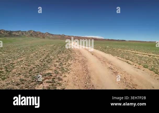 Aerial view Drone shot dusty country road with rocky mountains ...