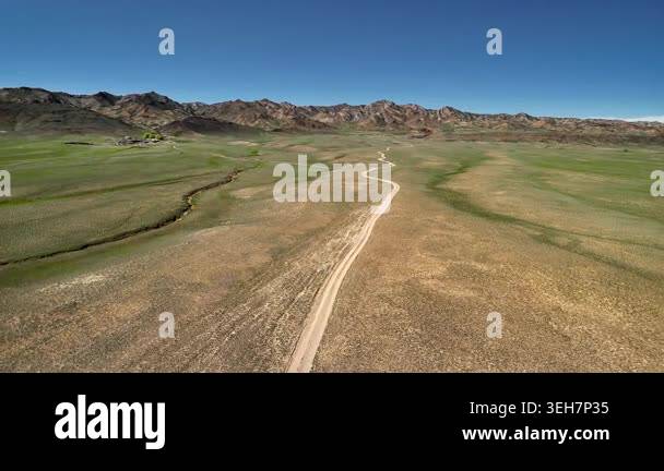 Aerial view Drone shot dusty country road with rocky mountains ...