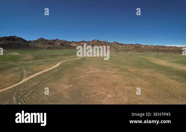 Aerial view Drone shot dusty country road with rocky mountains ...