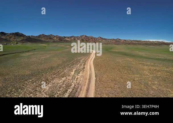 Aerial view Drone shot dusty country road with rocky mountains ...