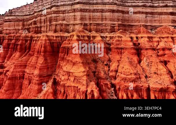 Erosion channels and horizontal strata on a bright red sandstone rock ...
