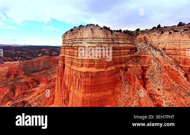 Layered sedimentary rock tower with erosion patterns and green ...